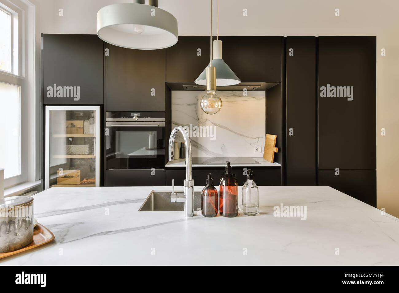 a kitchen with white marble countertops and black cabinetry in the ...