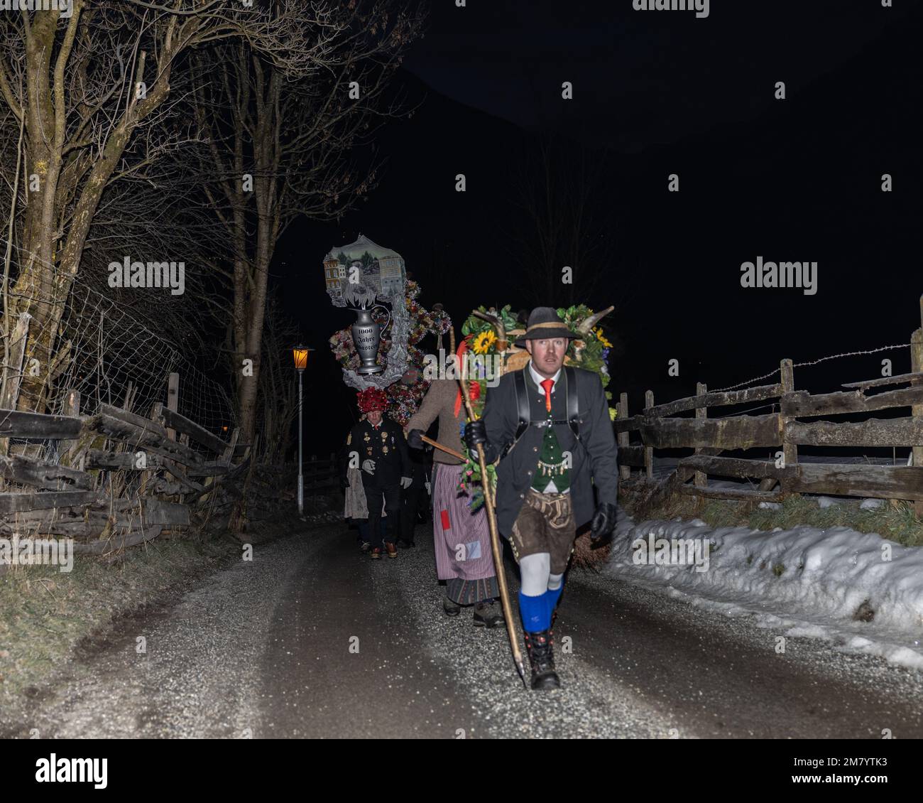 A bearer of bells leads a perchten procession along a country road in ...