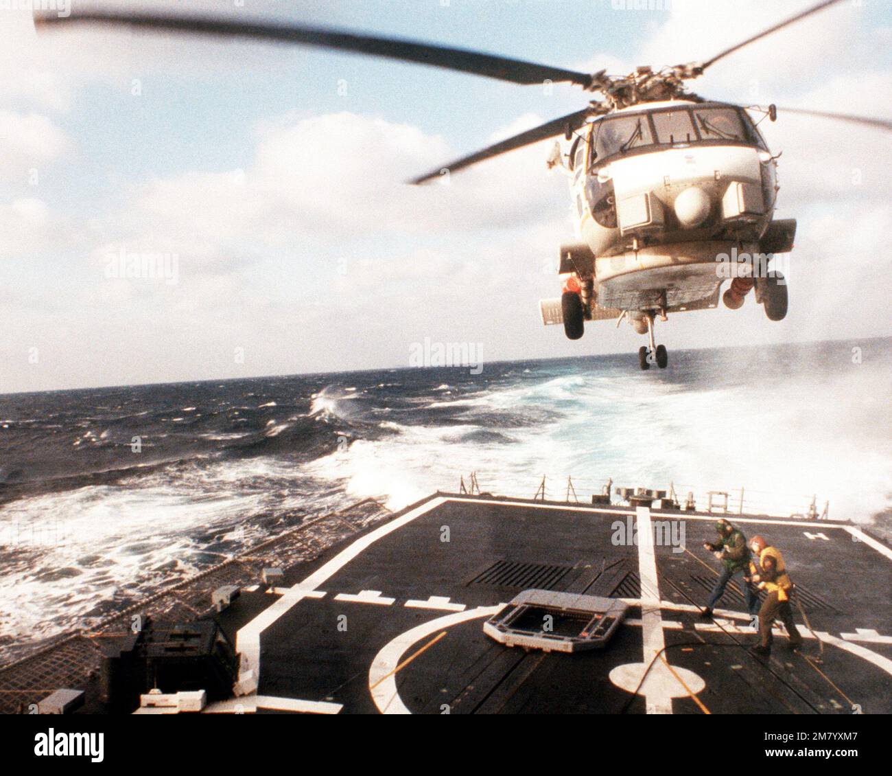Two crewmen direct an SH-60B Seahawk helicopter preparing to land ...