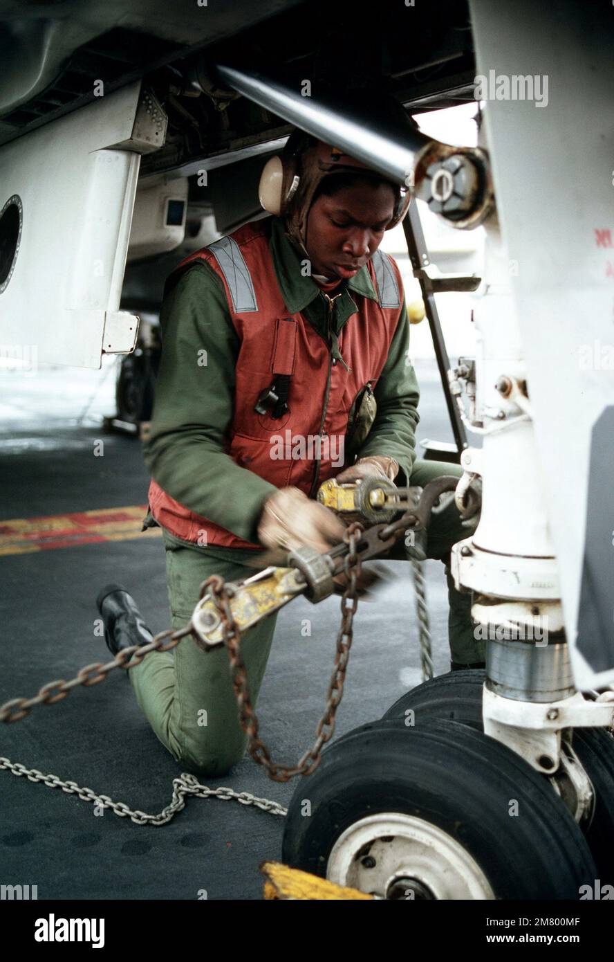 A member of the flight deck crew secures an aircraft to the flight deck ...