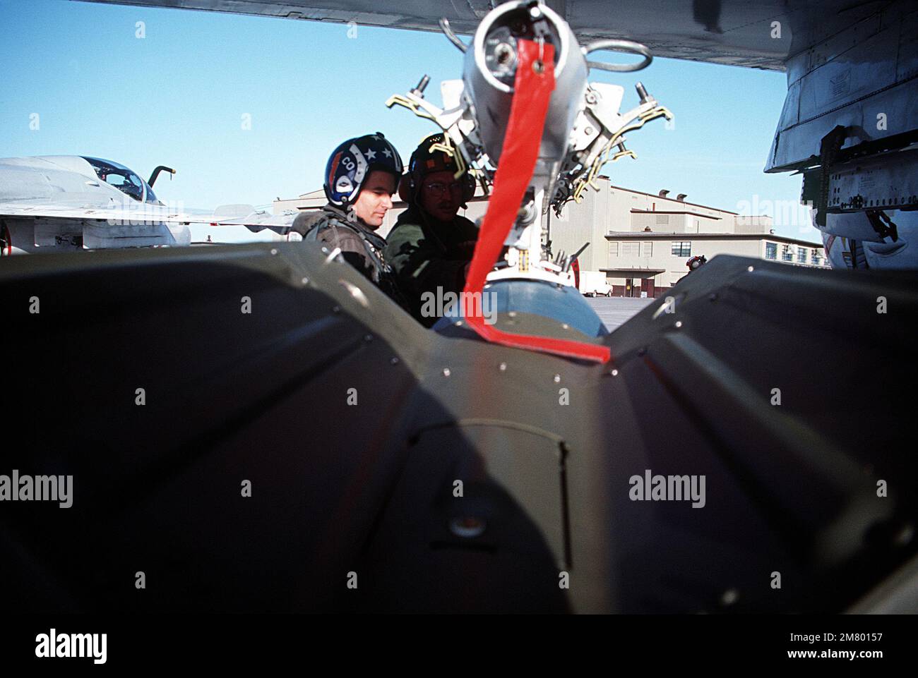 Ground crewman prepare to load a bomb onto the pylon of an A-6E ...