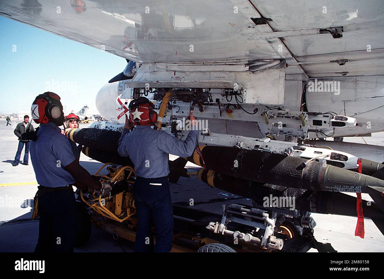 Ground crewman prepare to load bombs onto the pylon of an A-6E Intruder ...