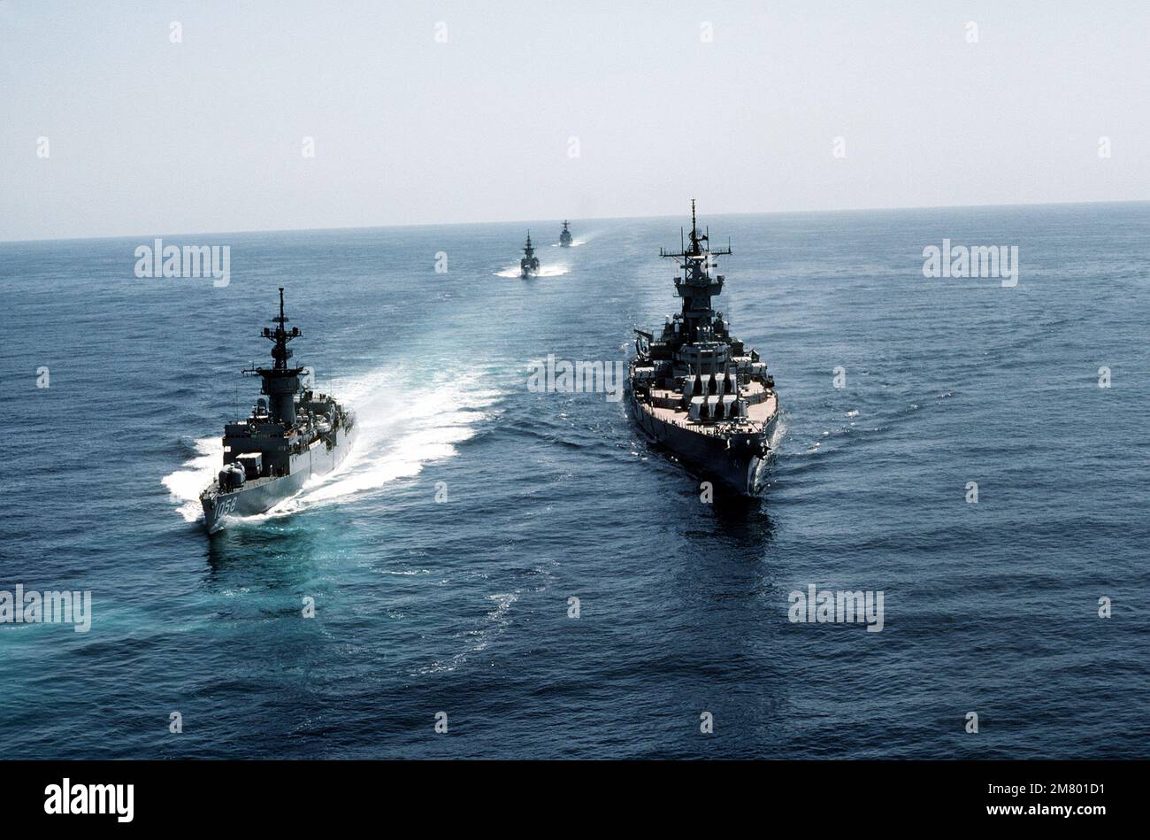 Aerial bow view of the battleship USS NEW JERSEY (BB-62) (right) and ...