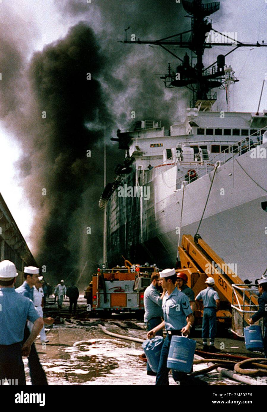 Firefighters at Pier 4 of the Naval Station work to extinguish a fire ...