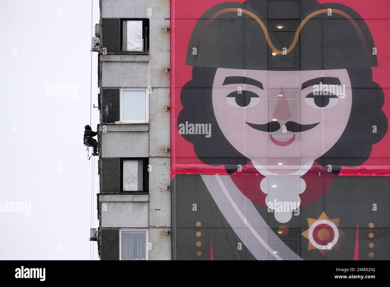 A worker descends a rope knocking ice floes off the facade of a ...