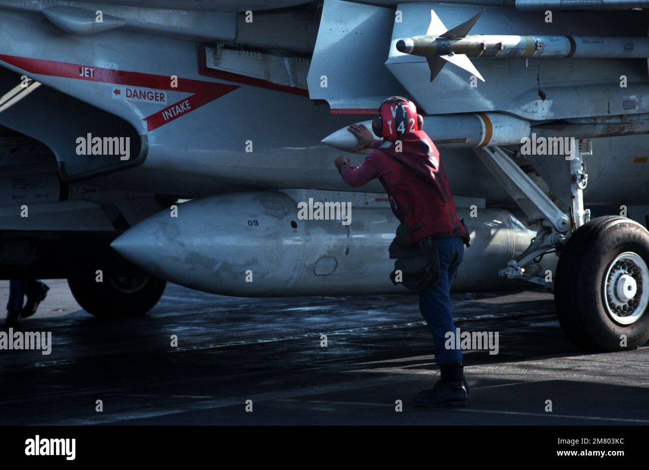 An ordnance crew member checks an AIM-7 Sparrow missile and an AIM-9 ...