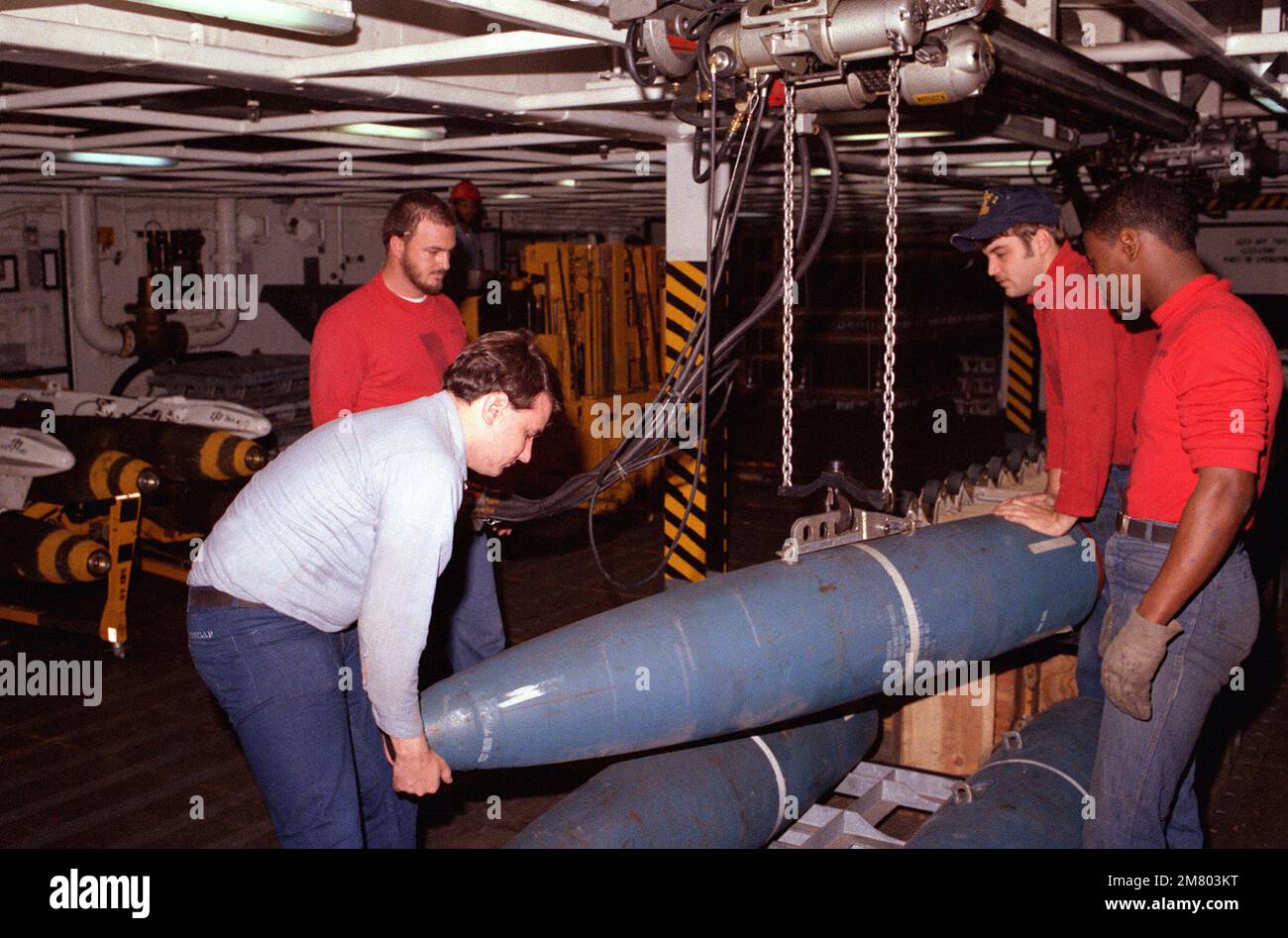 Aviation ordnancemen use an overhead hoist to move a 500-pound bomb in ...