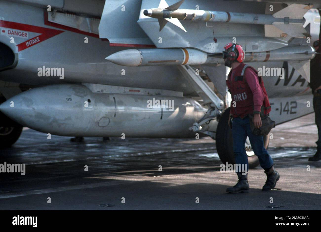An ordnance crew member checks an AIM-7 Sparrow missile and an AIM-9 Sidewinder missile attached ...