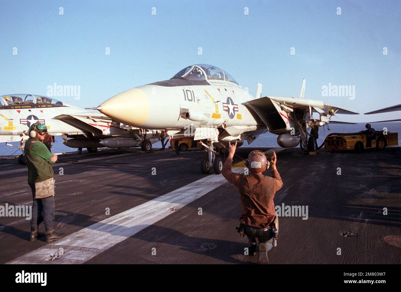 A plane captain signals to the pilot of a Fighter Squadron 143 (VF-143) F-14A Tomcat aircraft on ...
