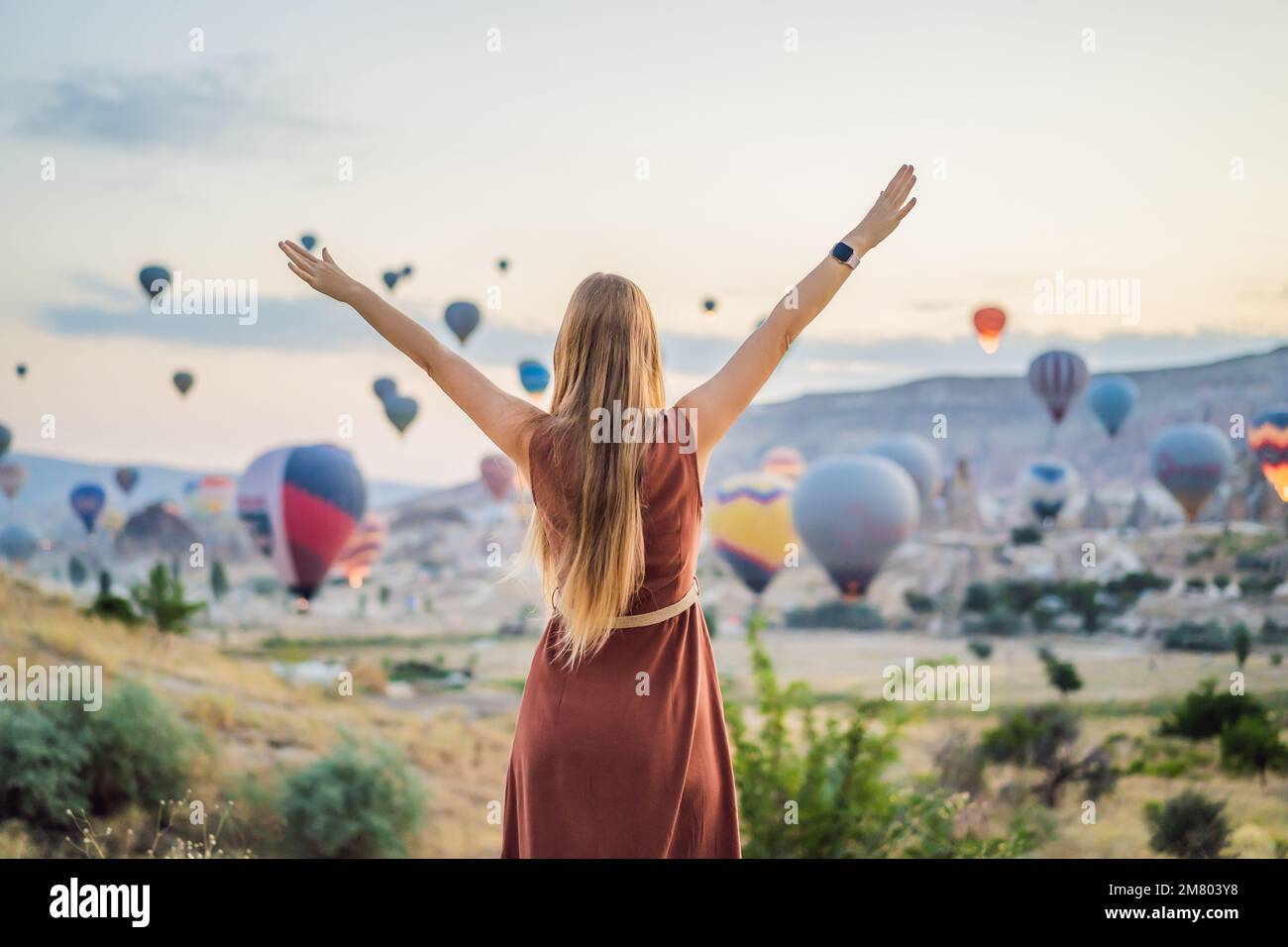 Tourist woman looking at hot air balloons in Cappadocia, Turkey. Happy ...