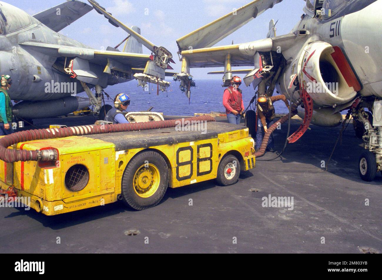 Sailors use an air hose from an MD-3A tow tractor to turn over the ...