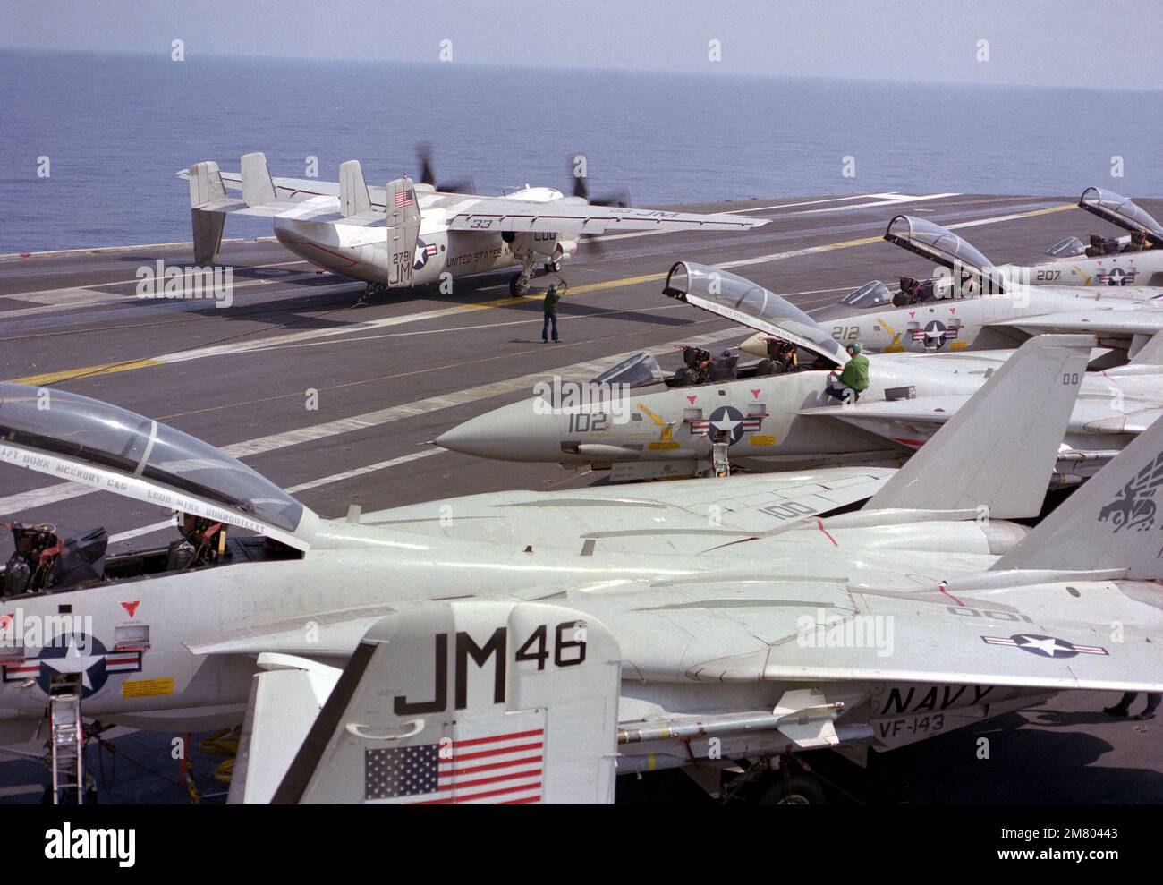 A C-2 Greyhound aircraft lands beside a row of F-14A Tomcat aircraft on ...