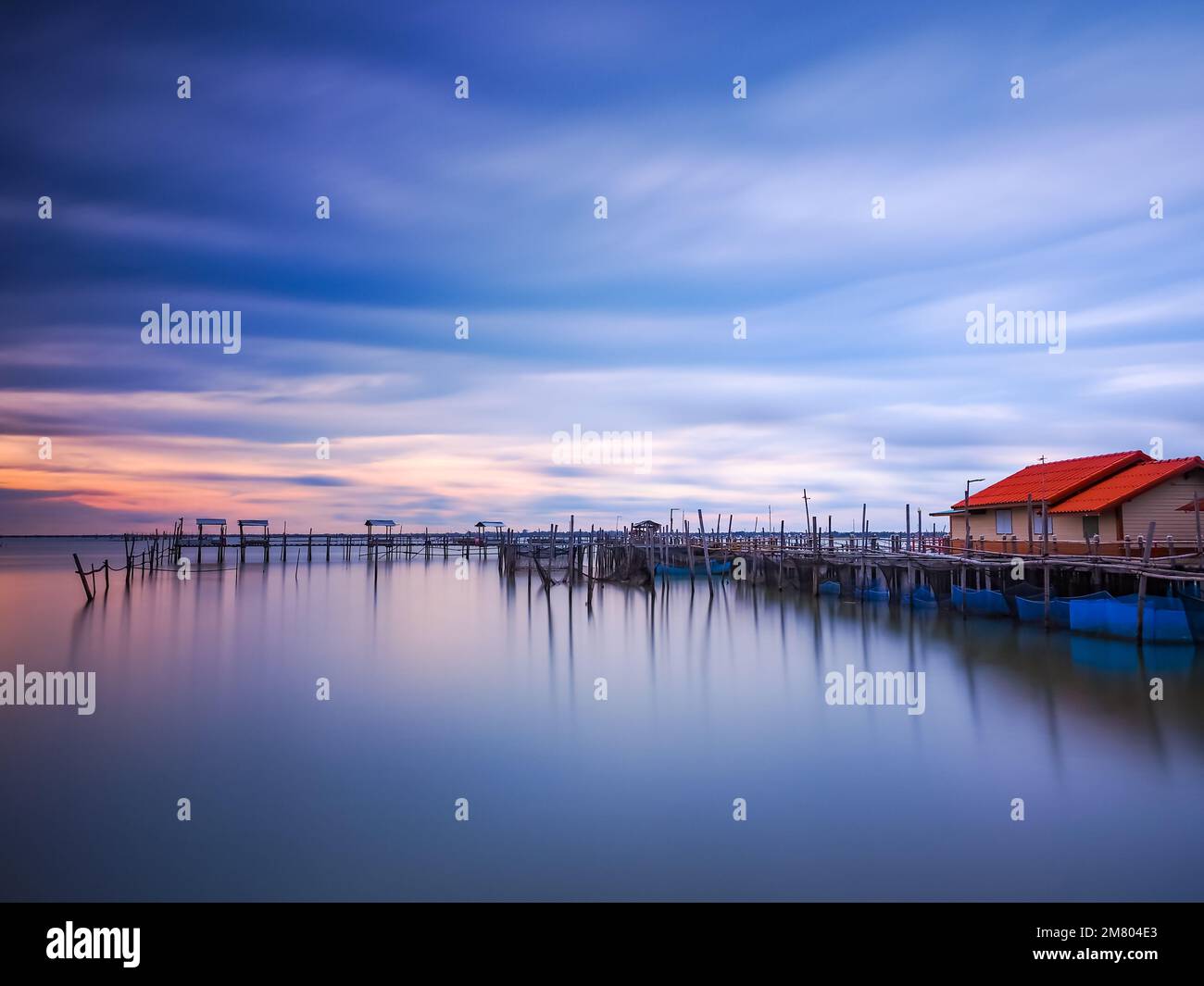 A long exposure shot of a sunset over a fishing village by the lake in ...