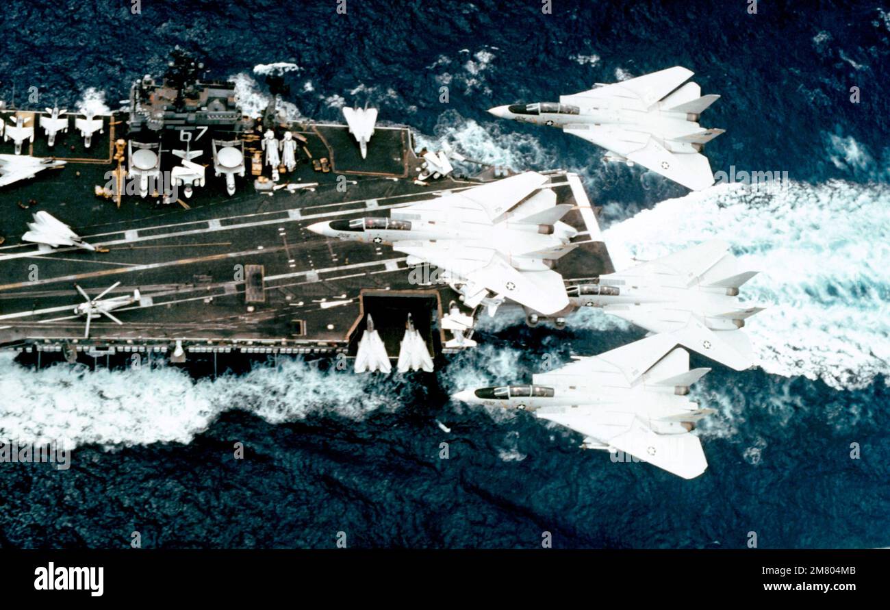An air-to-air left side view of four F-14 Tomcat aircraft flying over ...