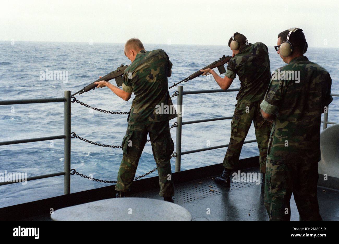 One Marine watches as two others fire M14 rifles off the fantail of the ...