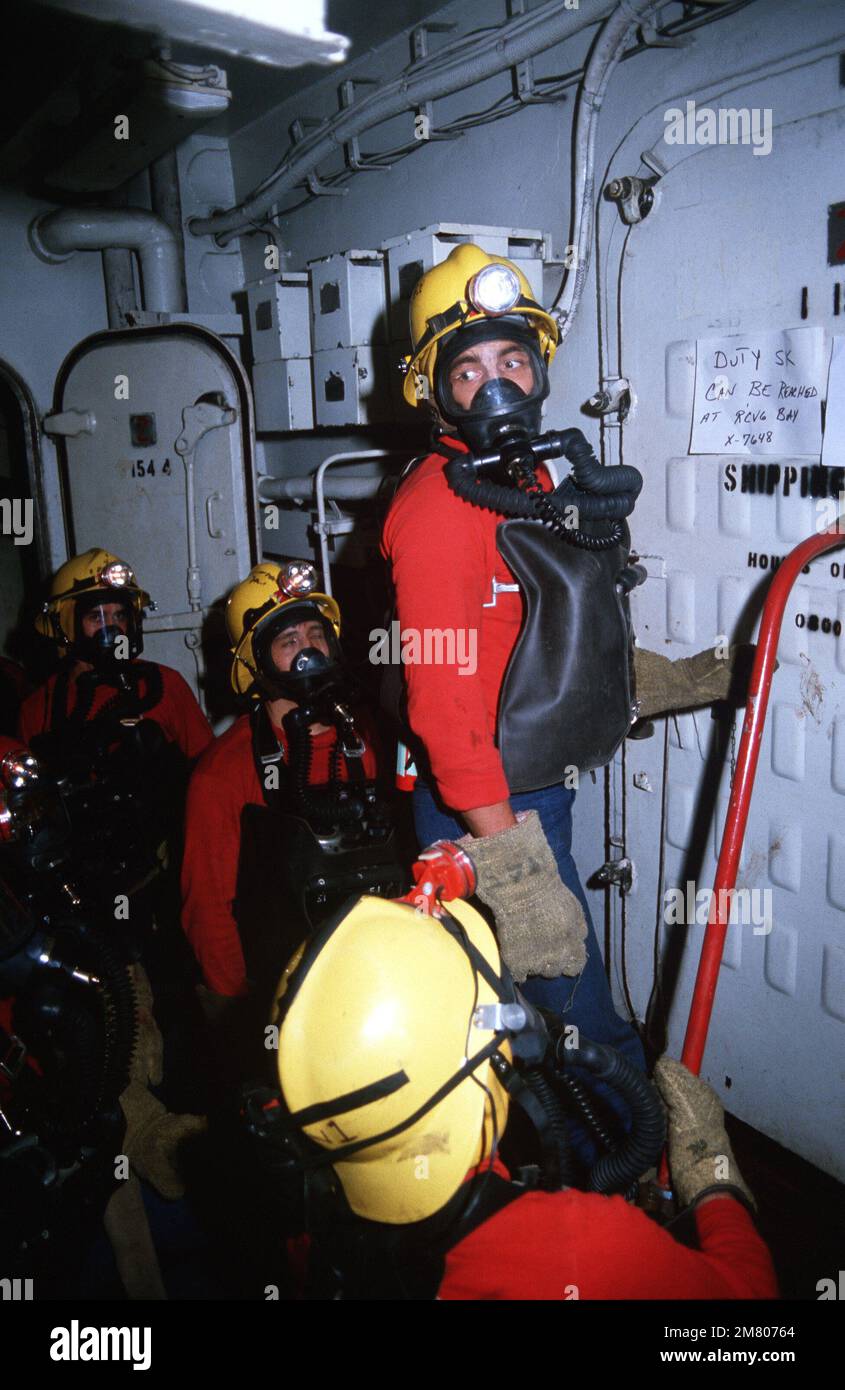 Crewmen, wearing oxygen breathing apparatus, prepare for a fire ...