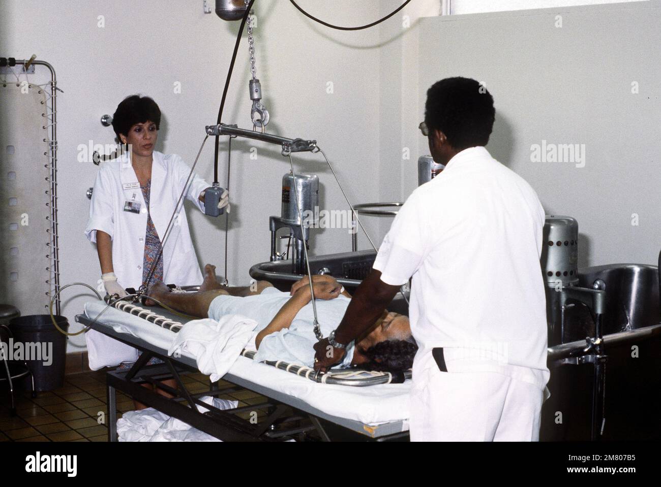 Physical therapists prepare to place a patient into a whirlpool tank at ...