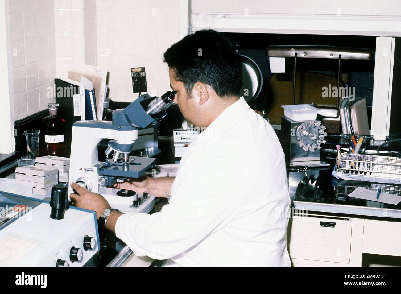 A lab technician uses a microscope to examine a specimen at Coco Solo ...