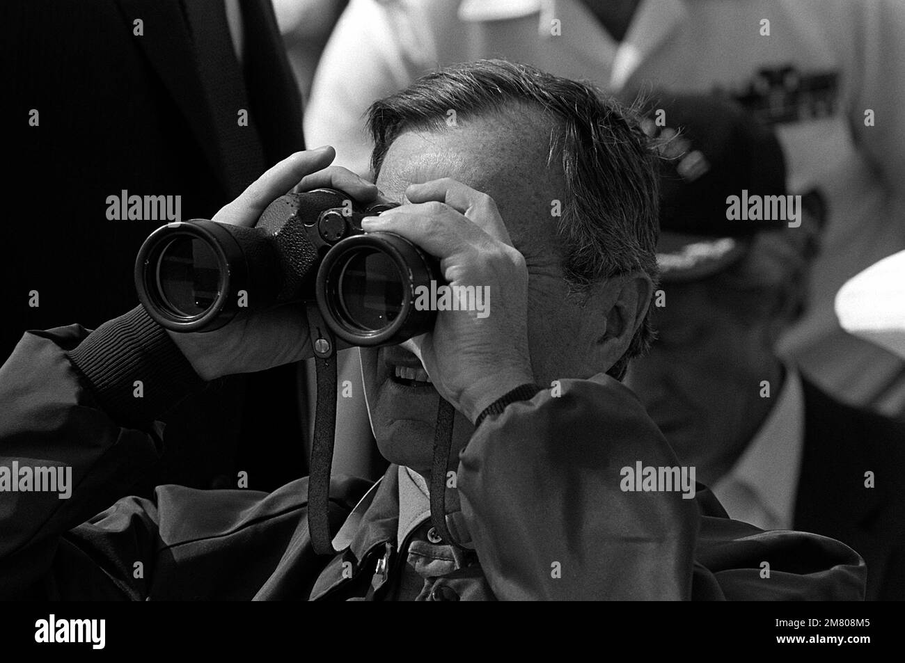 Vice President George Bush uses binoculars to watch an aerial ...