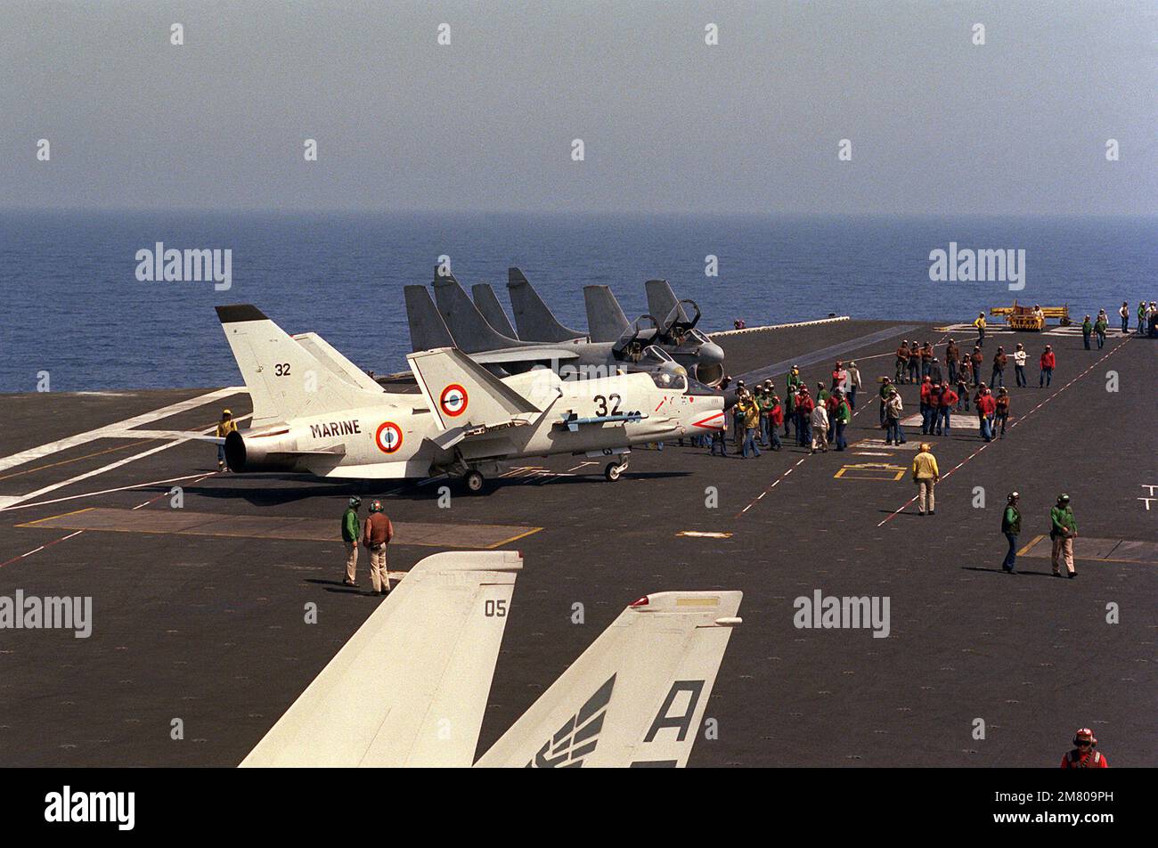 Crew members gather around two A-7E Corsair II and a French Marine F-8E ...