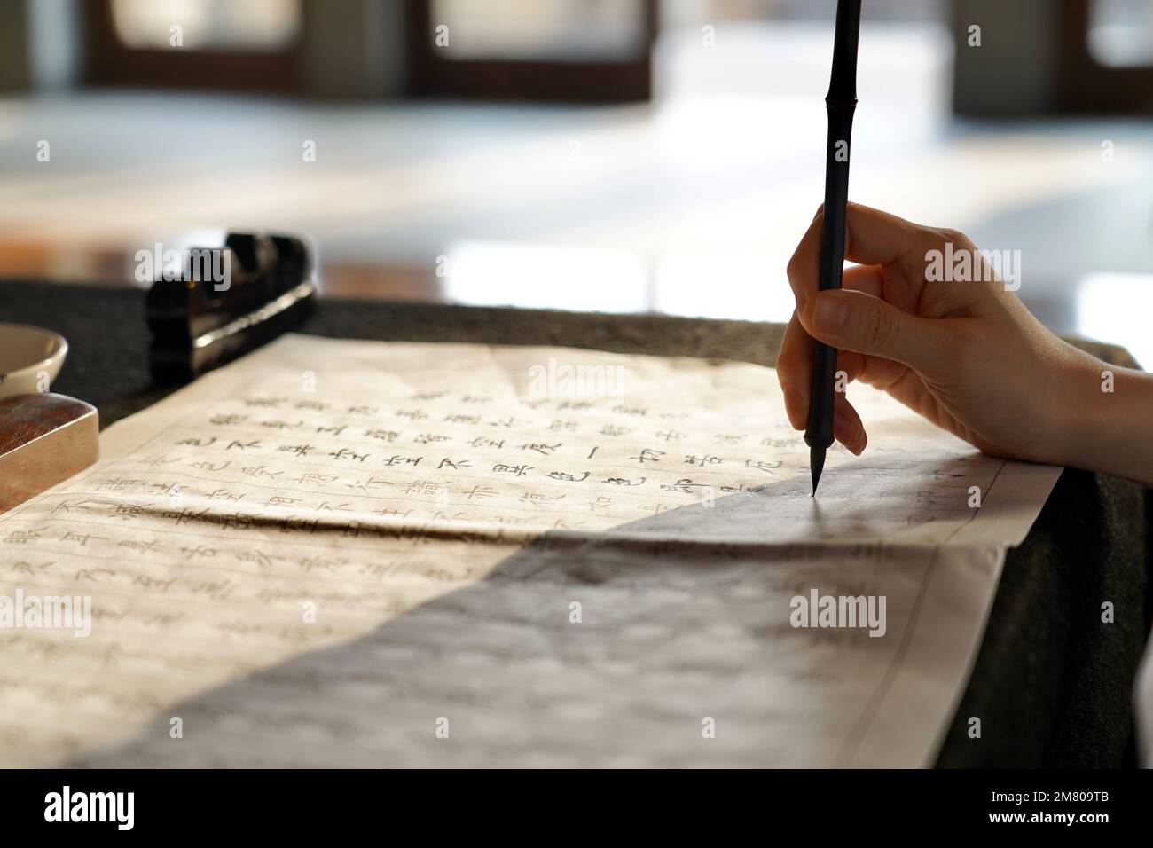 A shallow focus of a person's hand holding a traditional Chinese brush ...