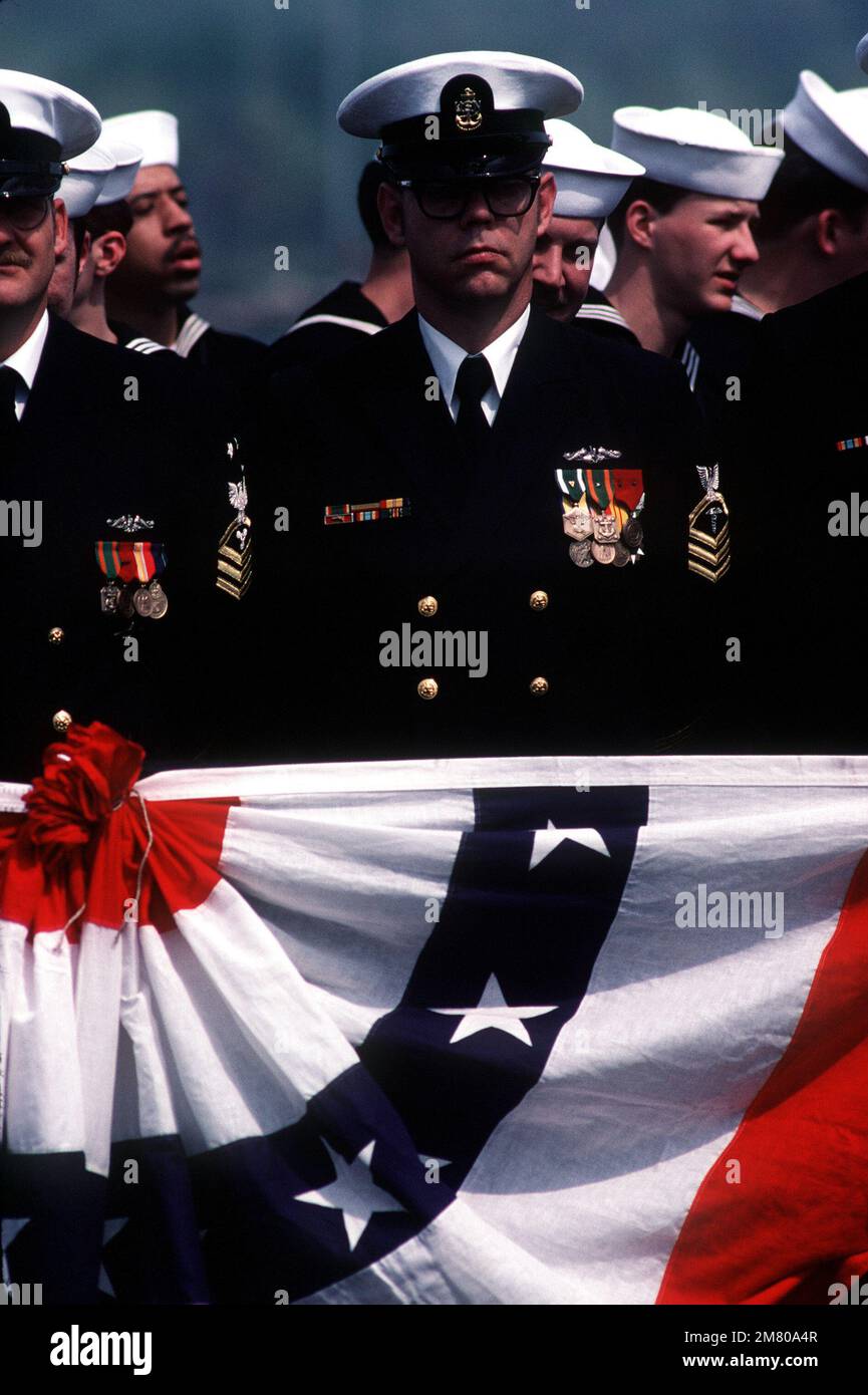 Crew members stand in formation on the deck of the nuclear-powered ...