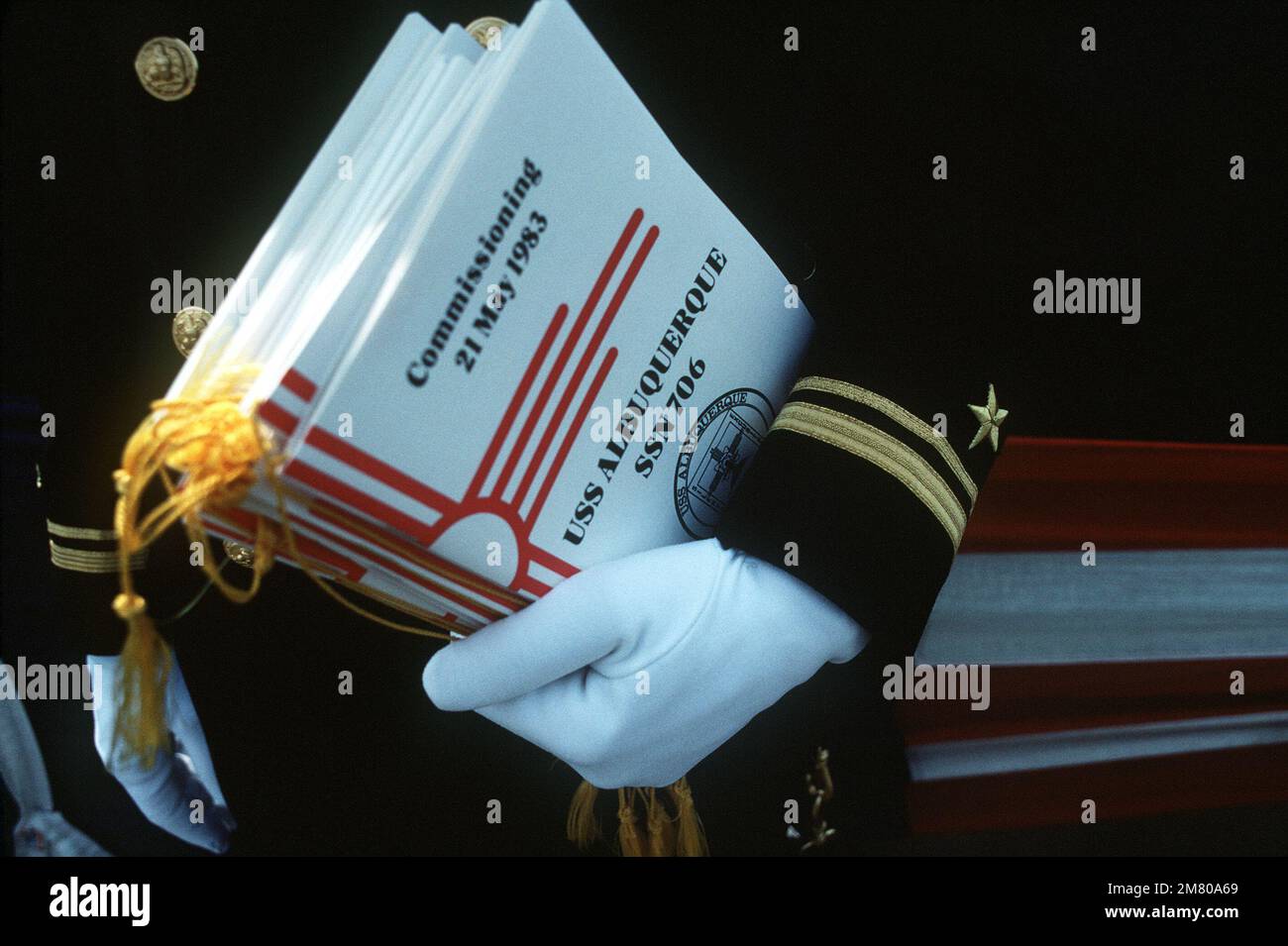 A crew member holds programs for the commissioning ceremony of the ...