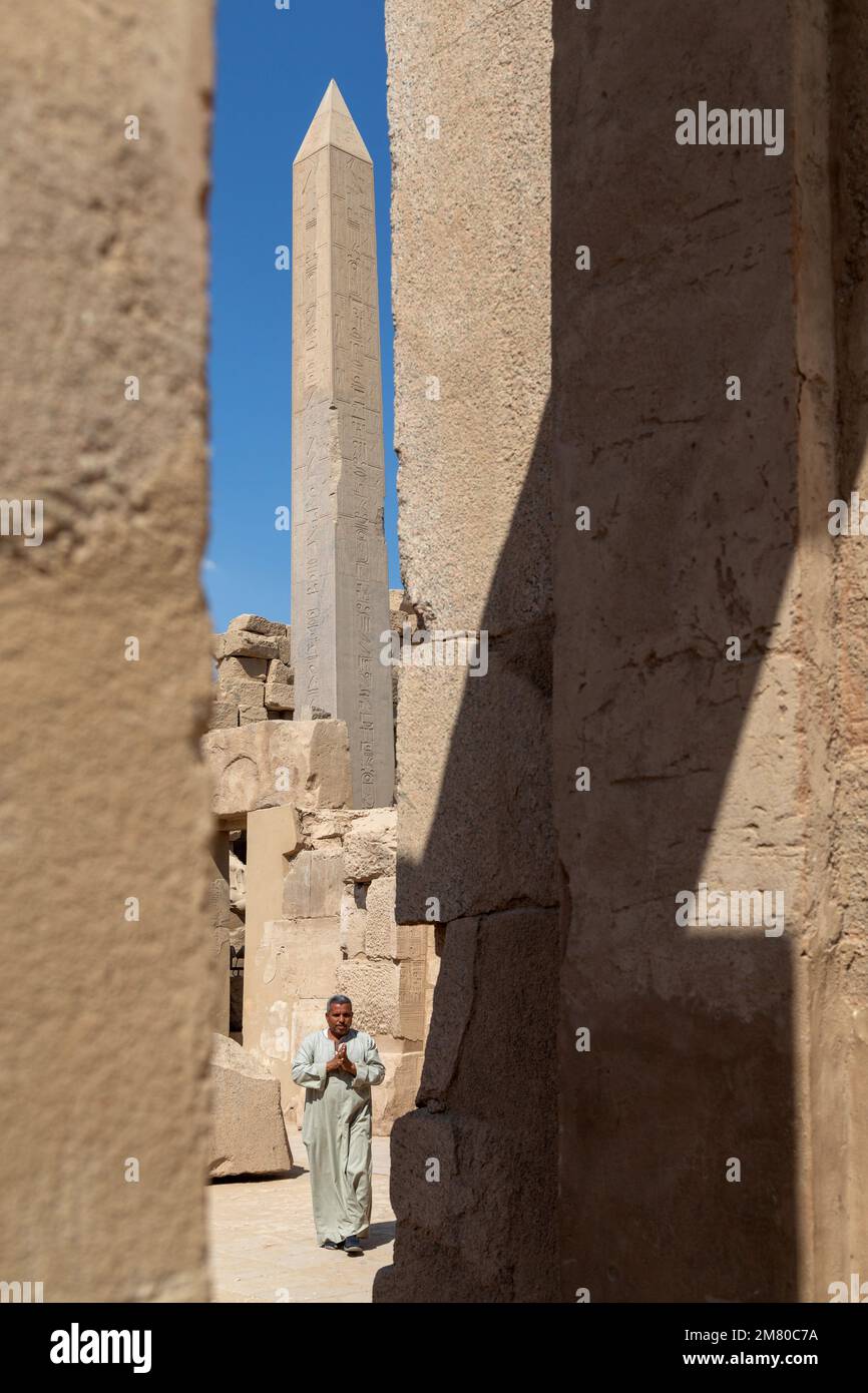 MAN IN A DJELLABA IN FRONT OF AN OBELISK ON THE PRECINCT OF AMUN-RE ...
