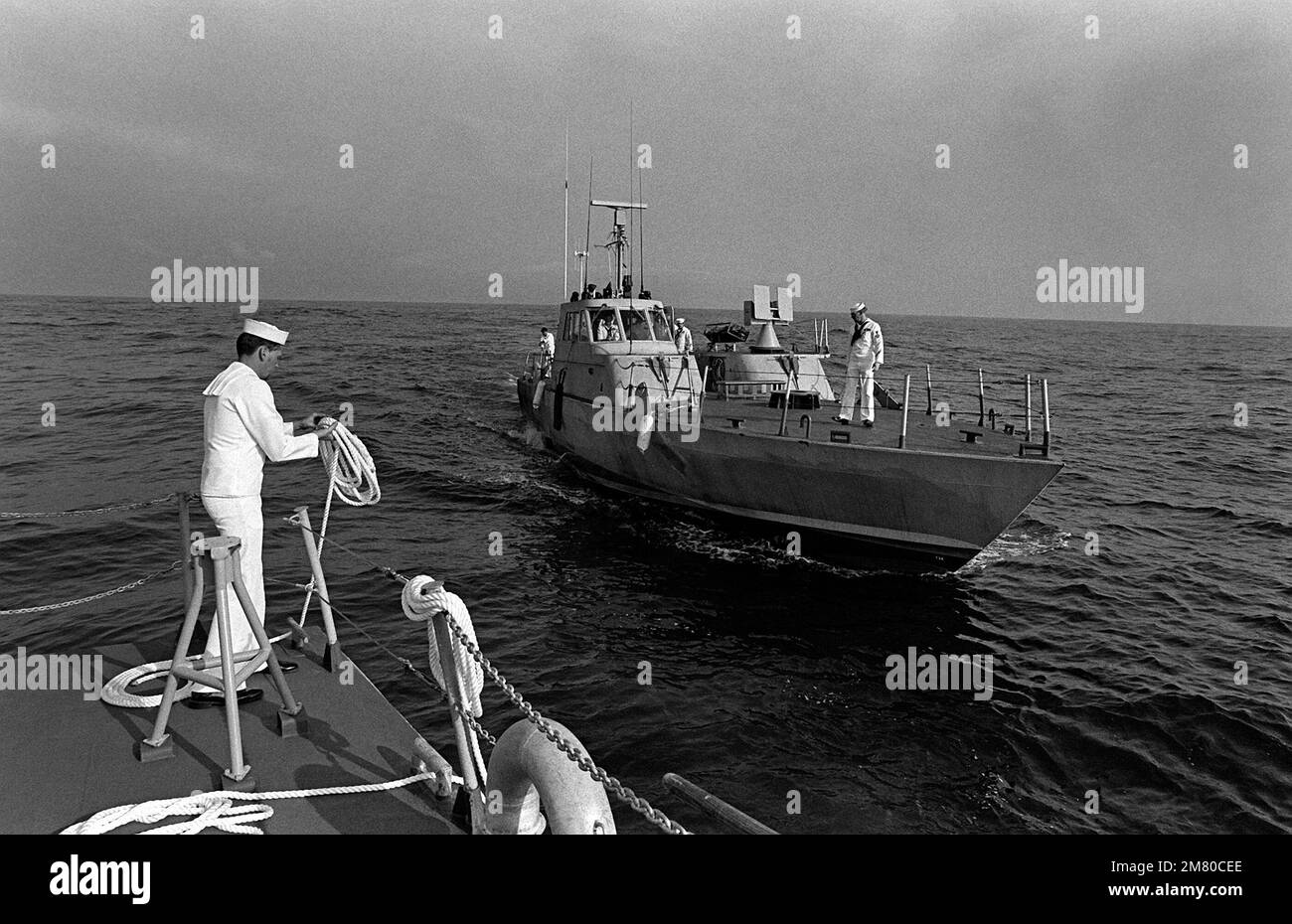 A seaman aboard a PB Mark III patrol boat prepares to cast a line to ...