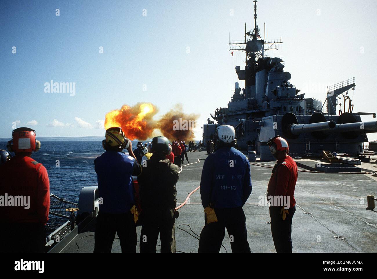 A 5-inch/38-caliber gun is fired off the port side of the battleship ...