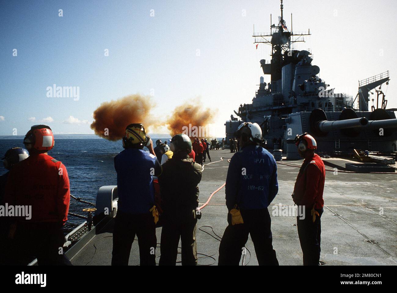 A 5-inch/38-caliber gun is fired off the port side of the battleship ...