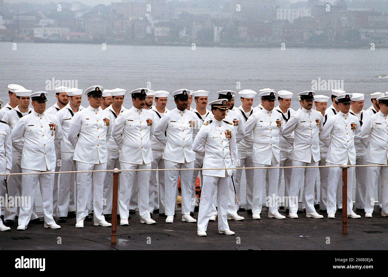Crew members stand at attention on the deck of the nuclear-powered ...