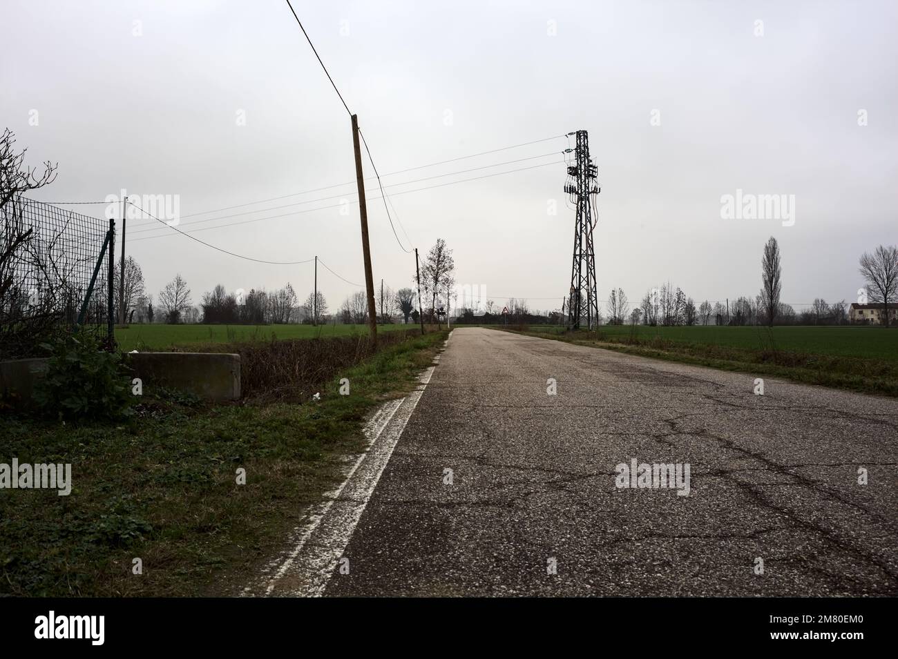 Empty road with wooden poles at its edge and fields bordering it on a ...