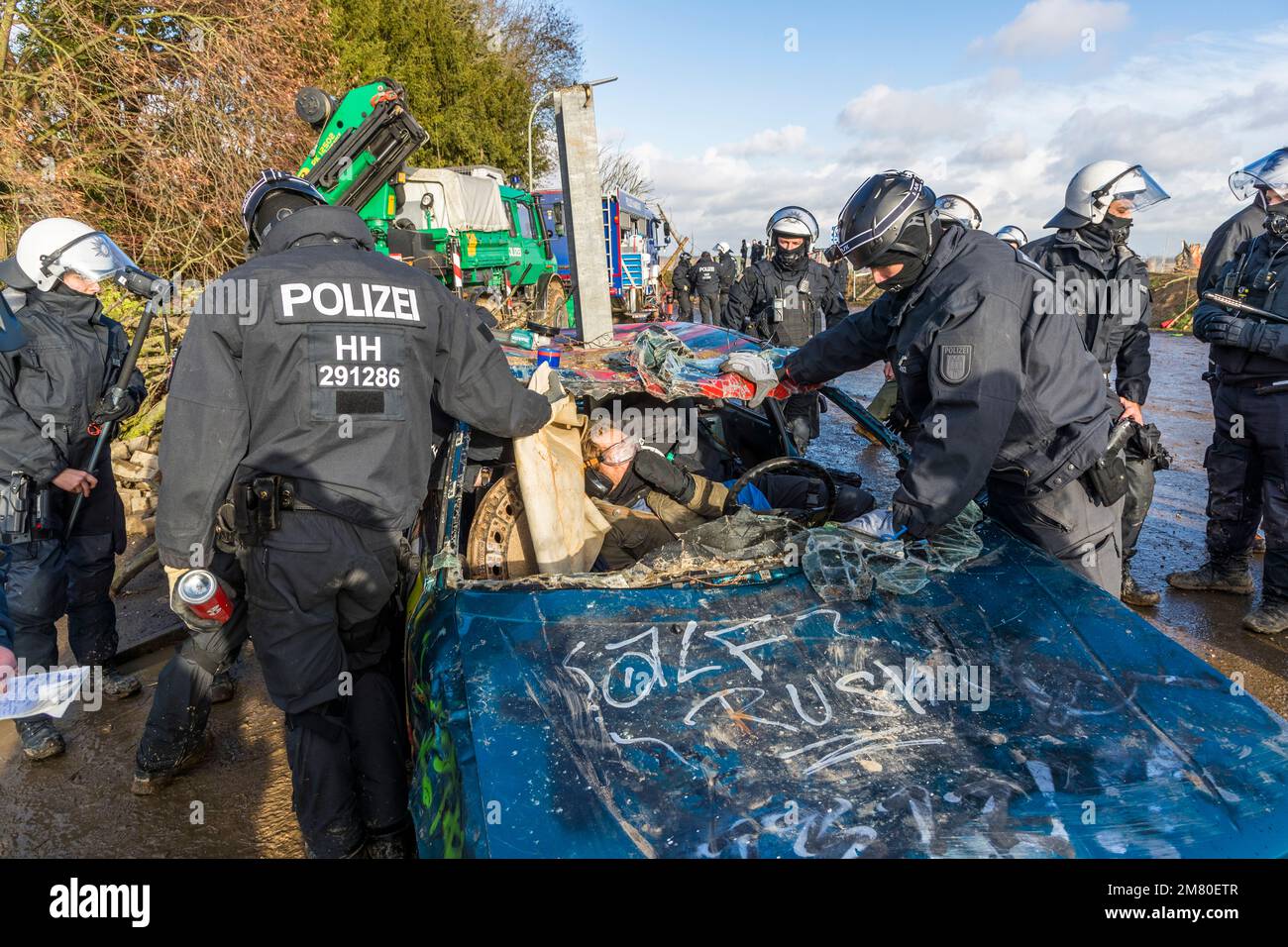 Police officers try to remove a climate activist from a wrecked car in ...