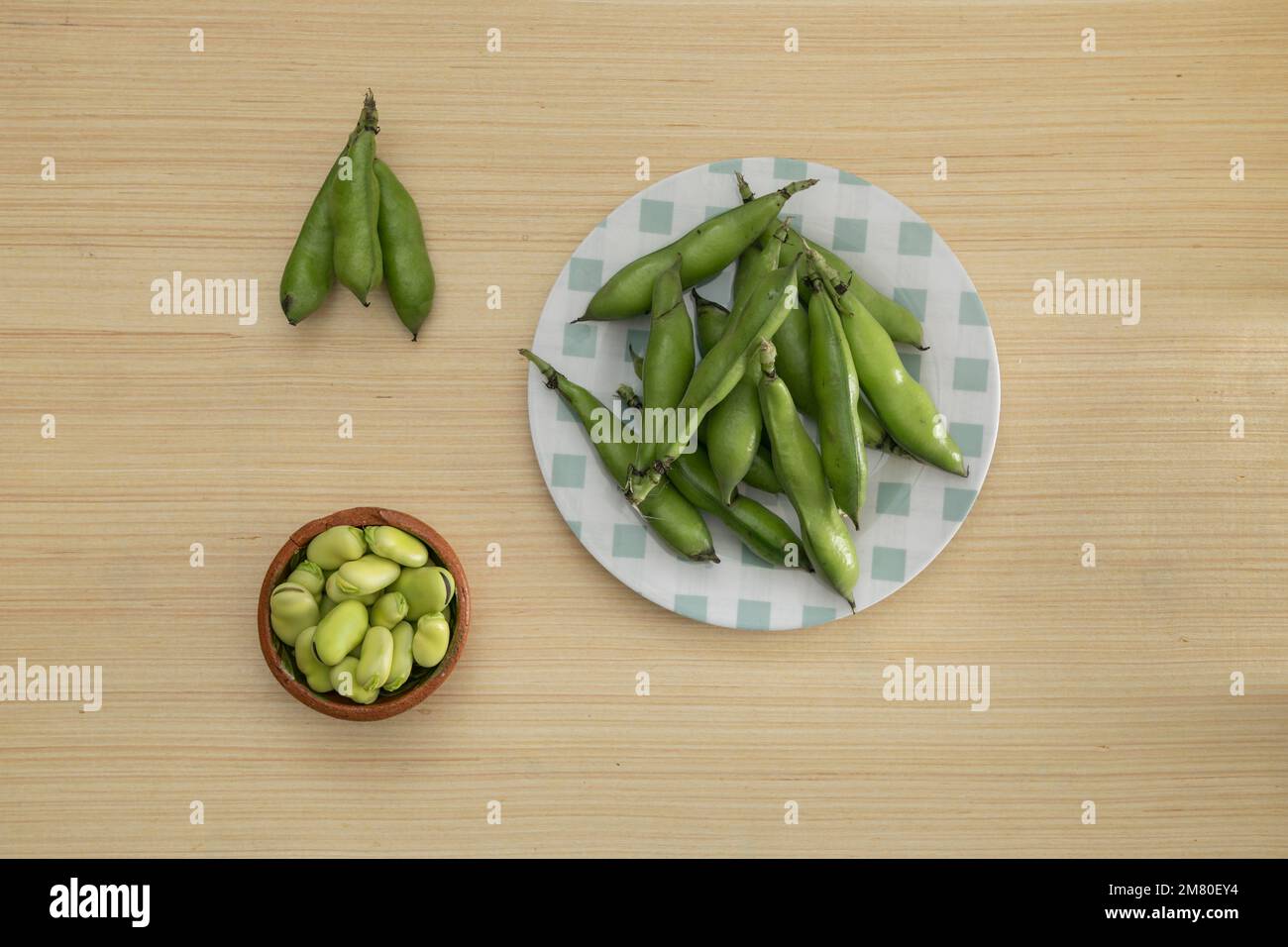 Top view of peeled and shelled fresh broad beans in plates on wooden ...