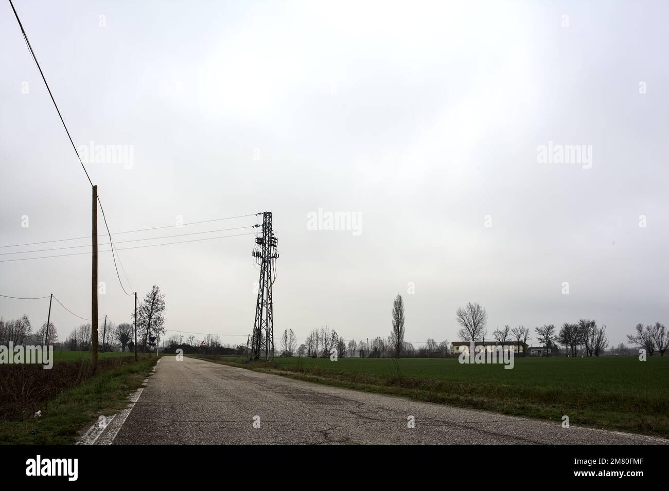 Empty road with wooden poles at its edge and fields bordering it on a ...