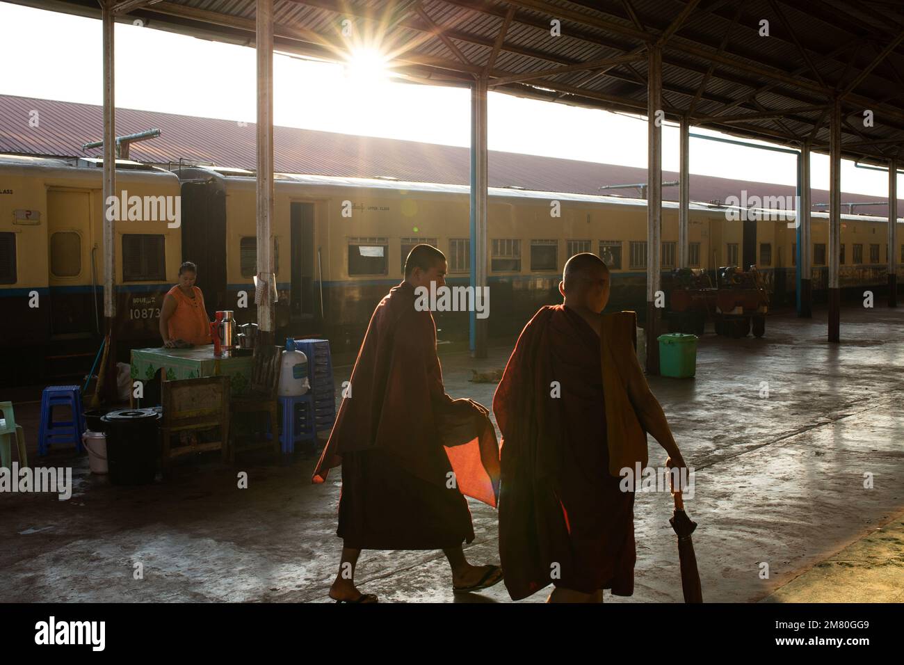 Myanmar daily life, sunrise. Monks walk through a myanmar train station ...