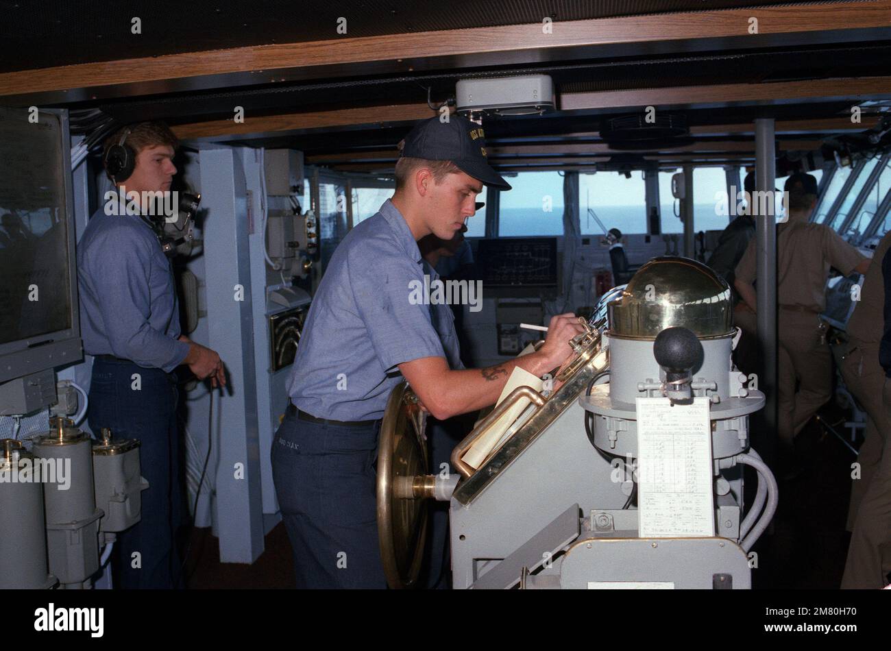 A crewmember mans the helm of the aircraft carrier USS KITTY HAWK (CV ...