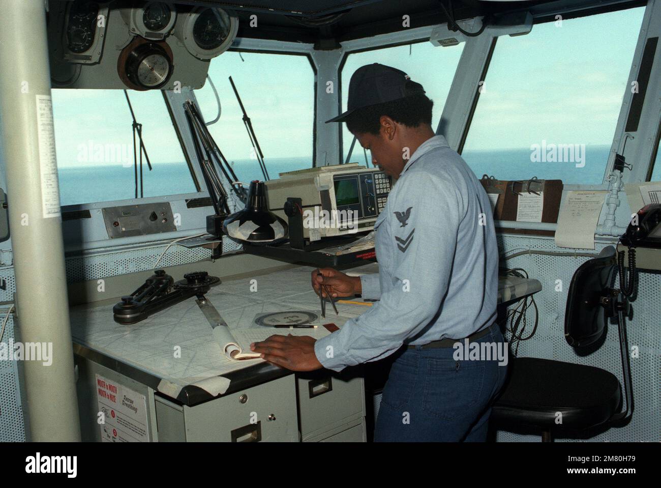 A quartermaster 2nd class checks the course at the navigators plot ...