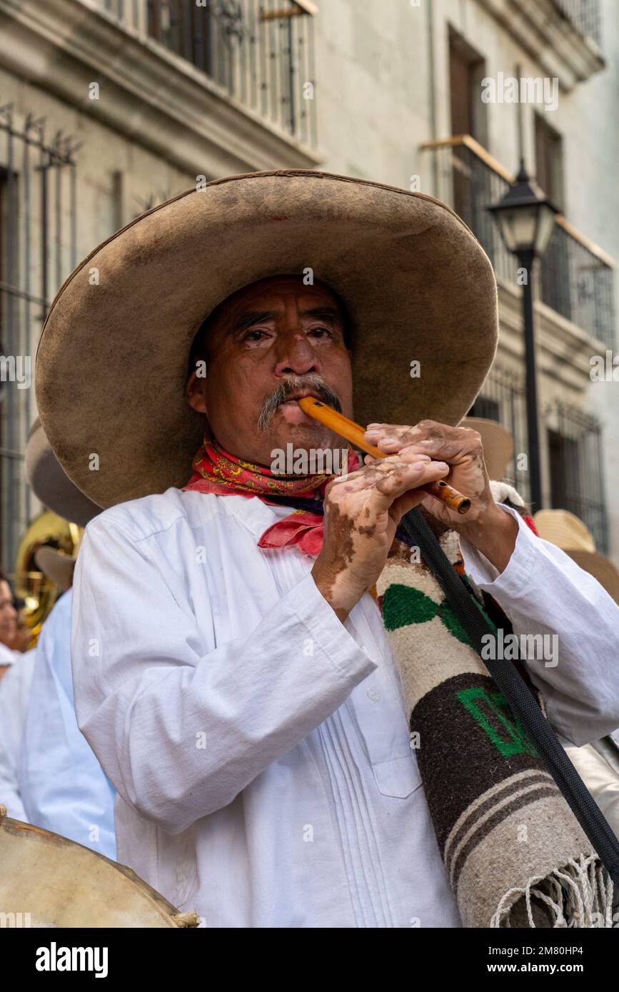 A musician with vitiligo playing a wooden flute in a parade during the ...
