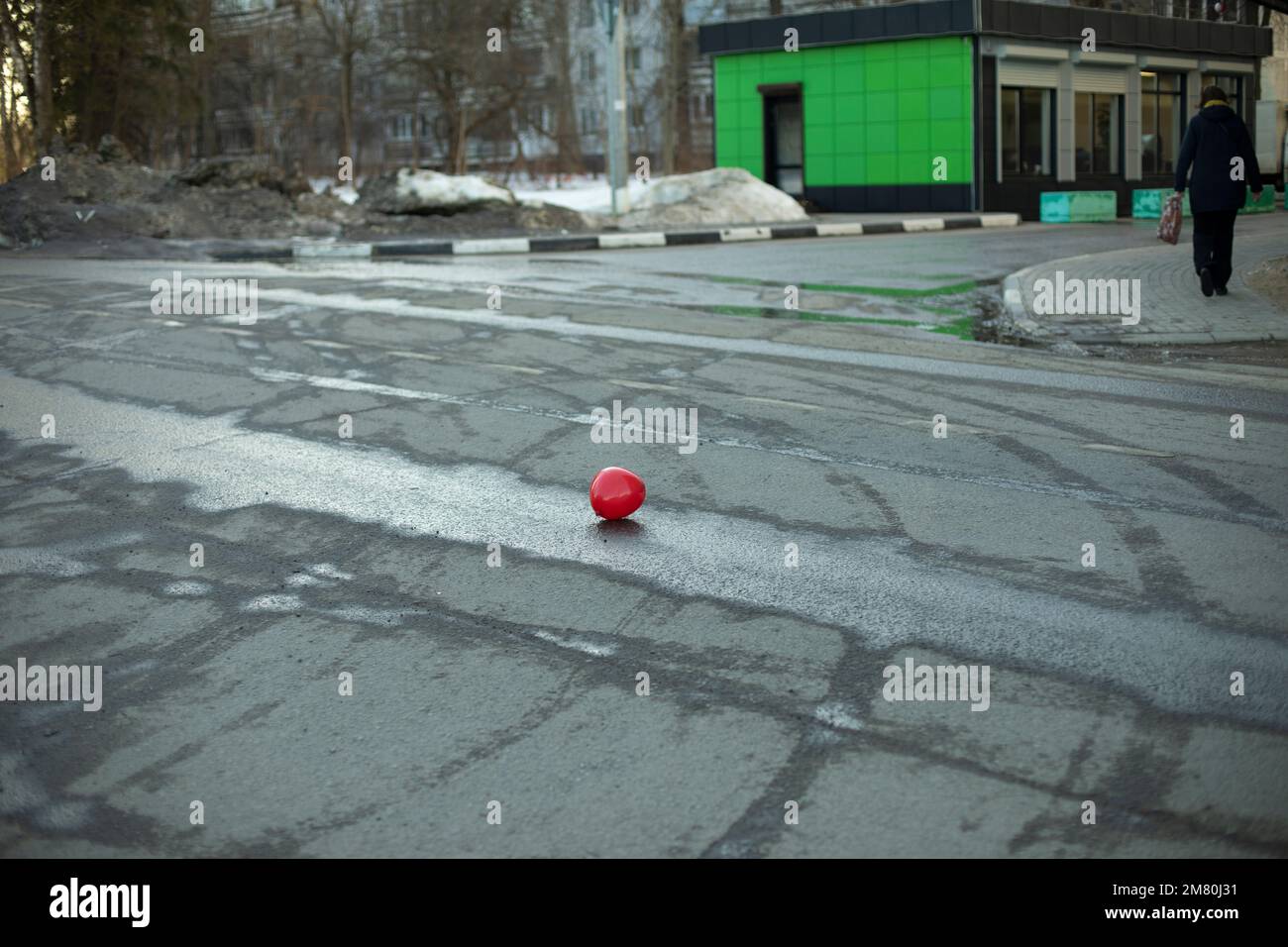 Red ball in city. Ball on road. Object that contrasts with its ...