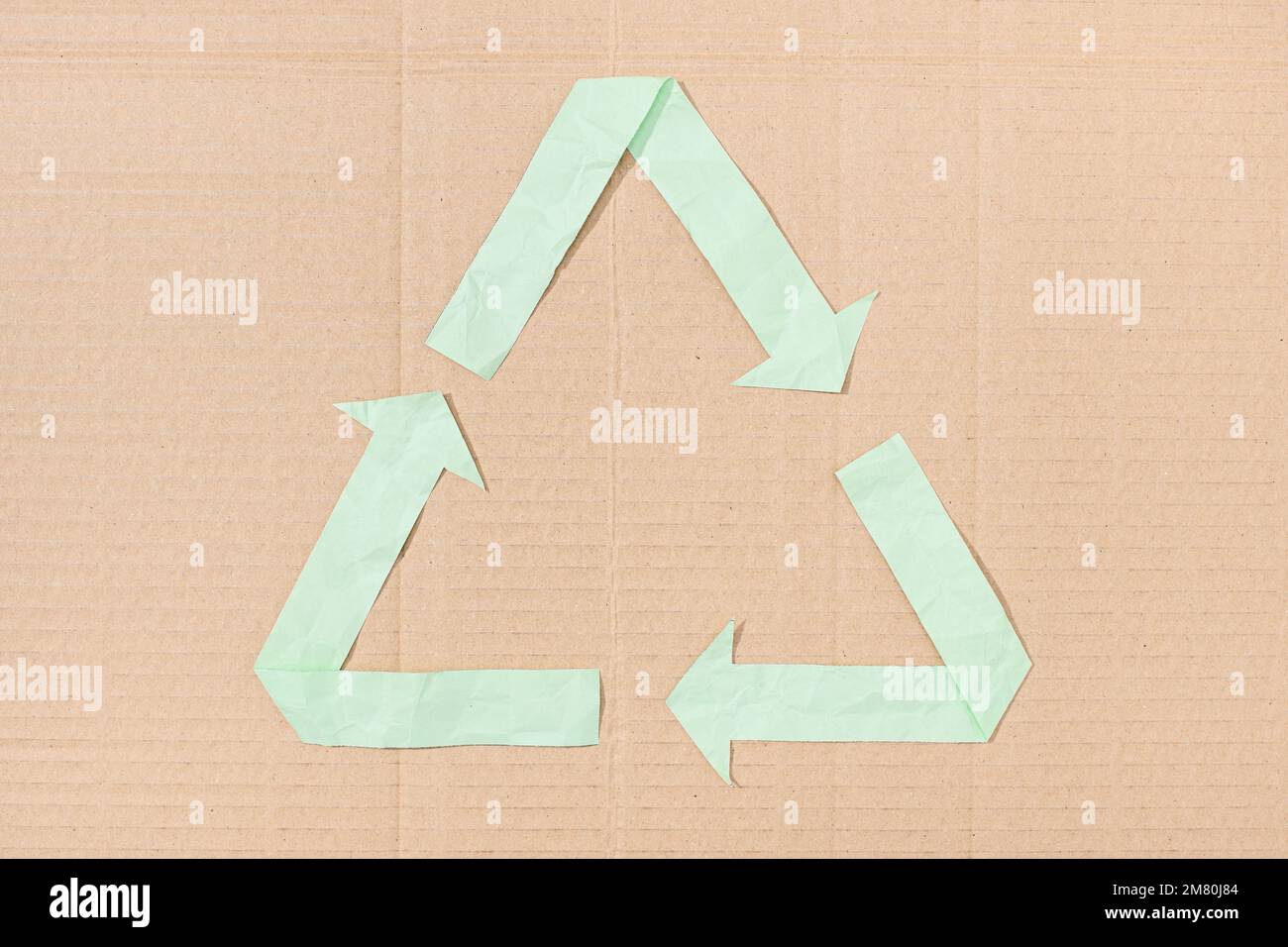Recycle symbol made of green paper cut on cardboard background texture ...