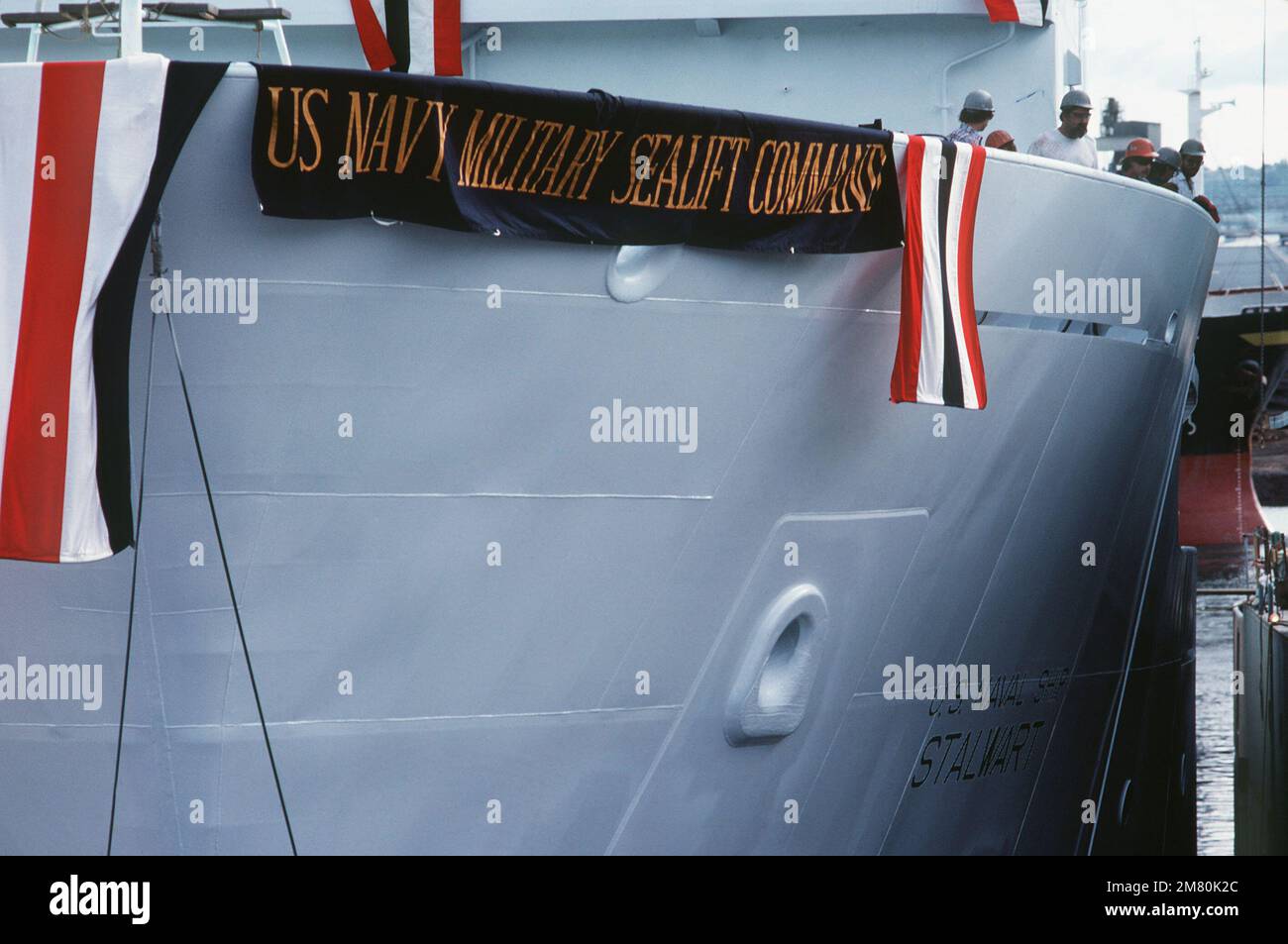 A Military Sealift Command banner hangs from the bow of the ocean ...