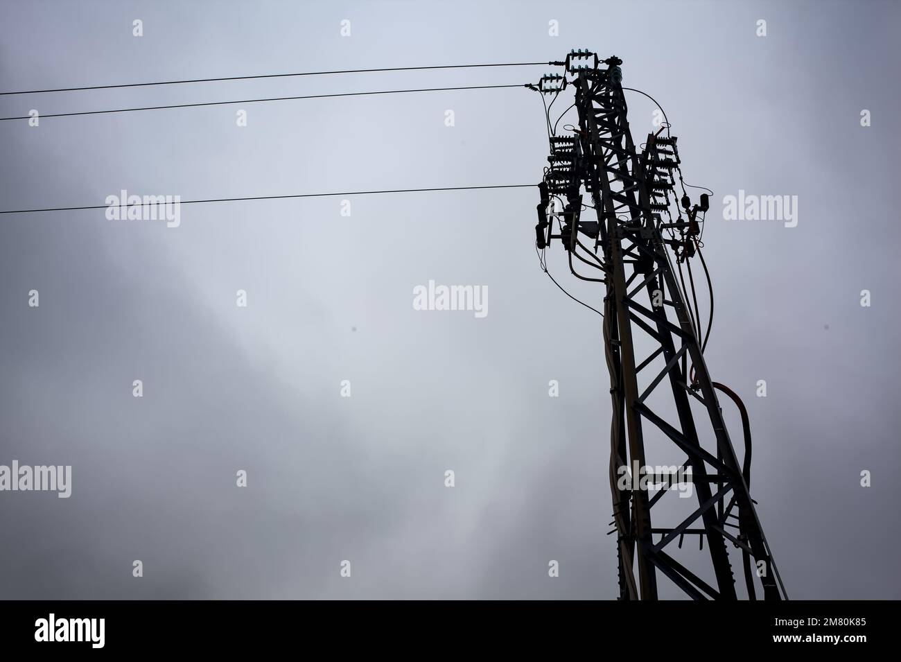 Electricity pylon with over head cables passing on it and a cloudy sky ...