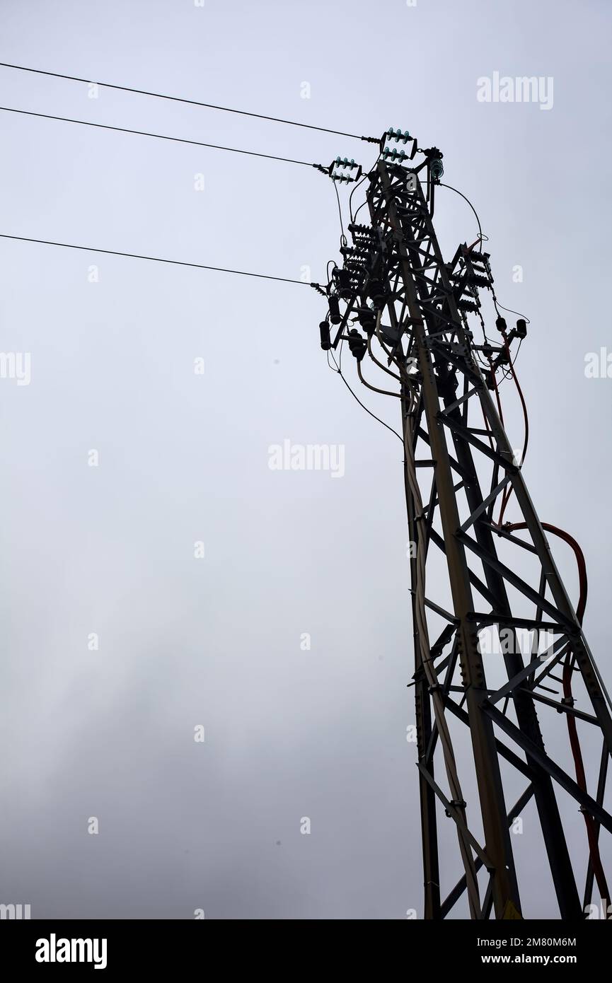 Electricity pylon with over head cables passing on it and a cloudy sky ...