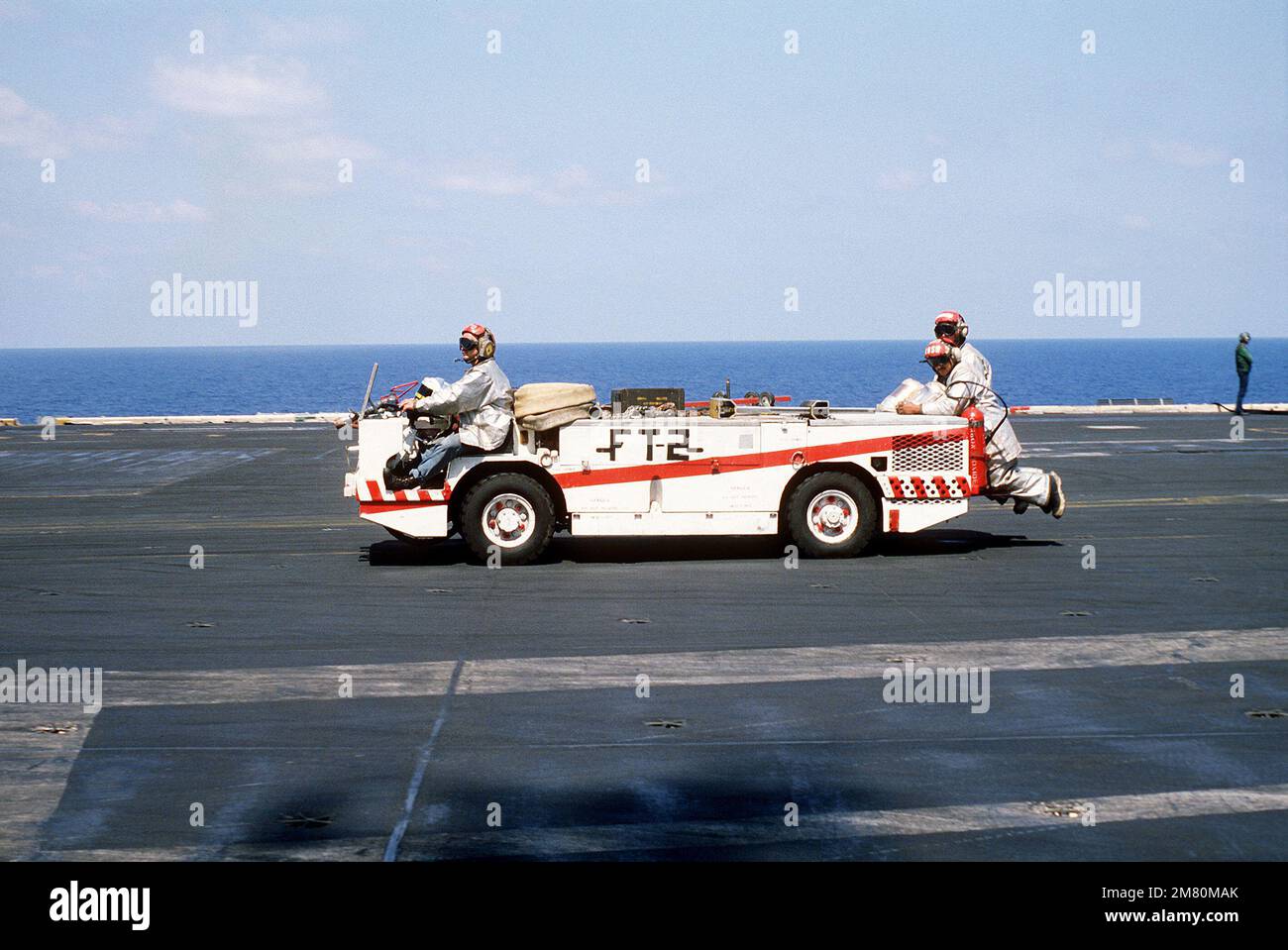 Firefighters wearing proximity suits ride in a damage control vehicle ...