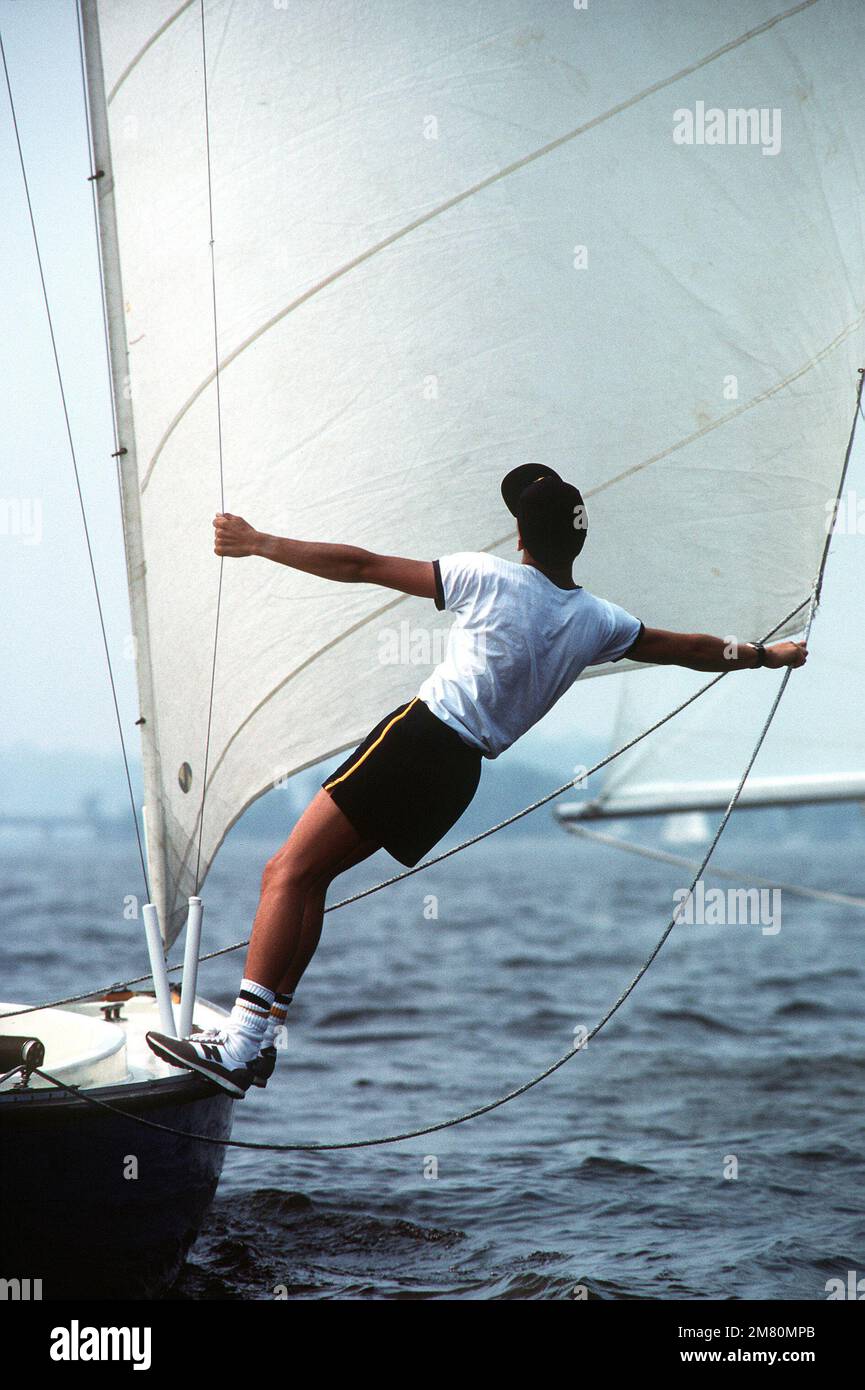 A plebe at the U.S. Naval Academy leans out over the water to spread ...