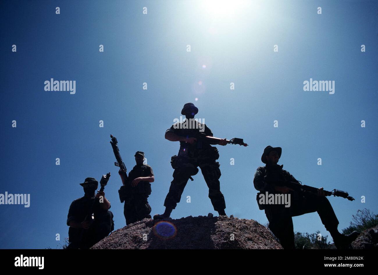 A silhouetted view of four members of an Air Base Ground Defense team ...