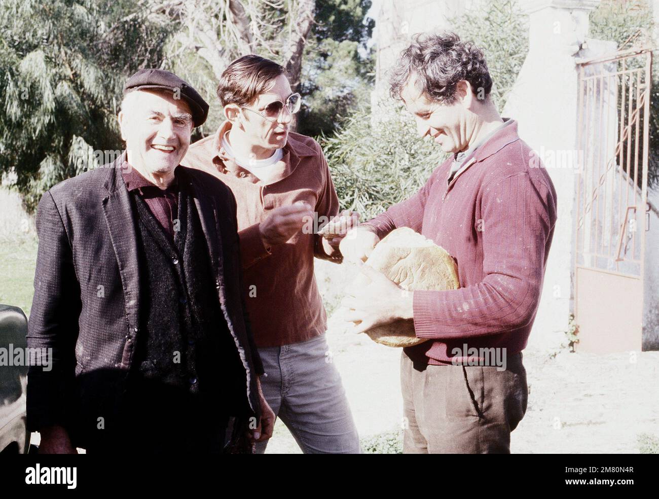 TSGT Bob Shields (center) is offered fresh bread by Peter Lakinthinos ...