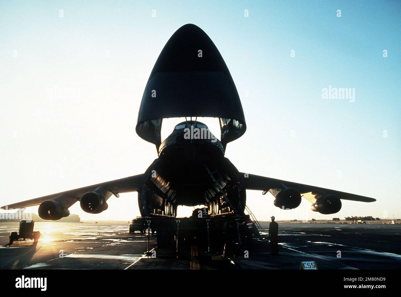 A C-5 Galaxy aircraft, on the flight line at sunrise, waits to be ...